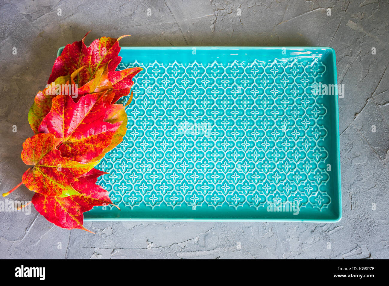 Festive autumnal table setting with bright red and yellow leaves with ...