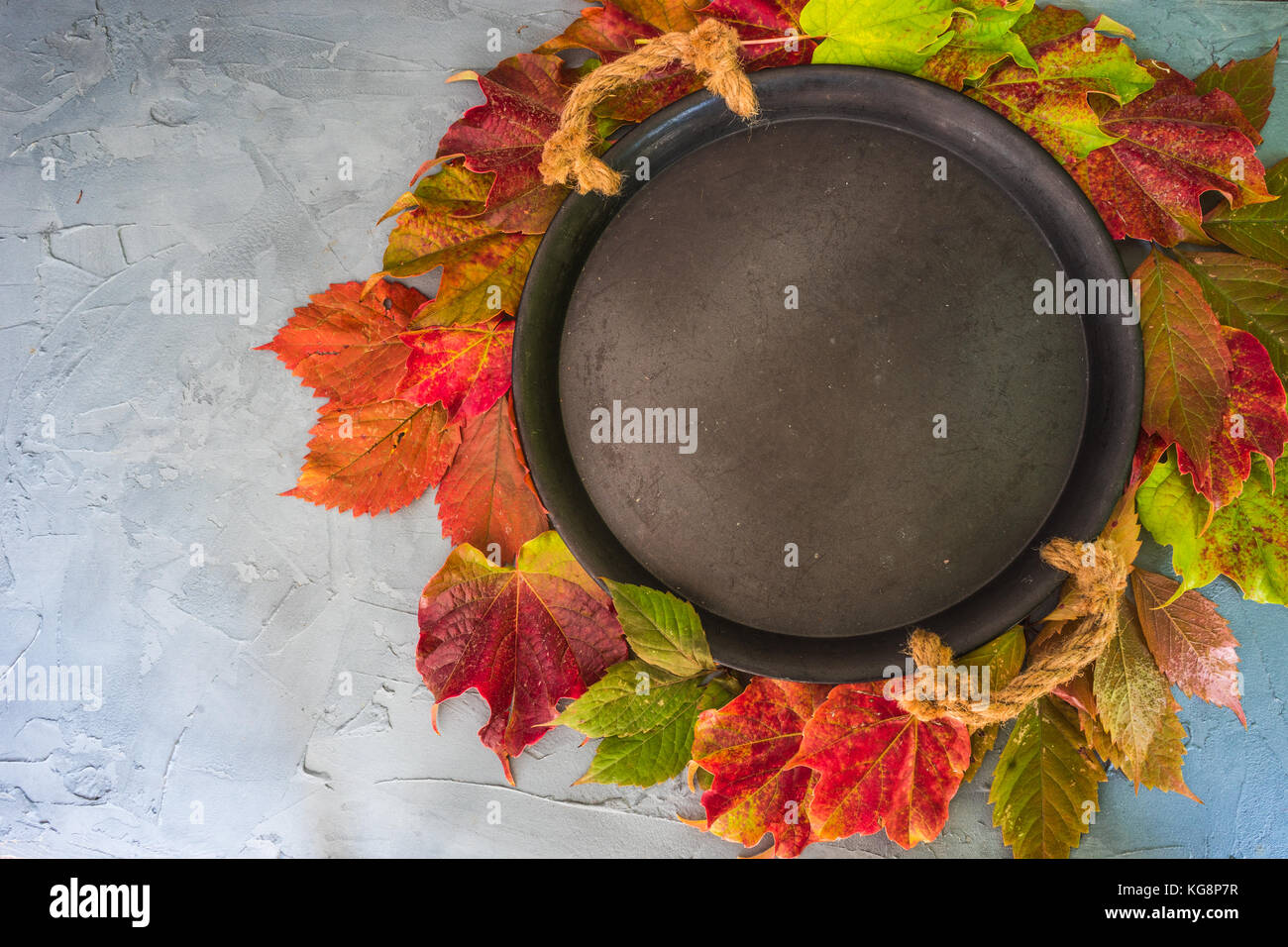 Festive autumnal table setting with bright red and yellow leaves with ...