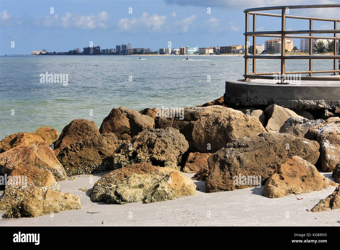 Rocks on the beach at the end of a concrete pier, that juts out into ...