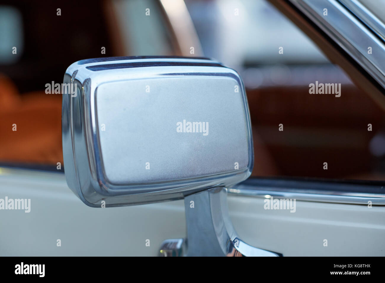 Chrome and white metal side view mirror on a vintage car viewed close ...