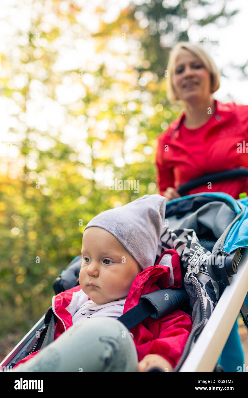 Running mother with contemplative child in stroller enjoying motherhood ...