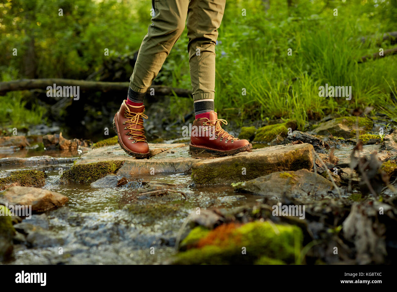 Woman hiker crossing a small mountain stream using natural rock ...