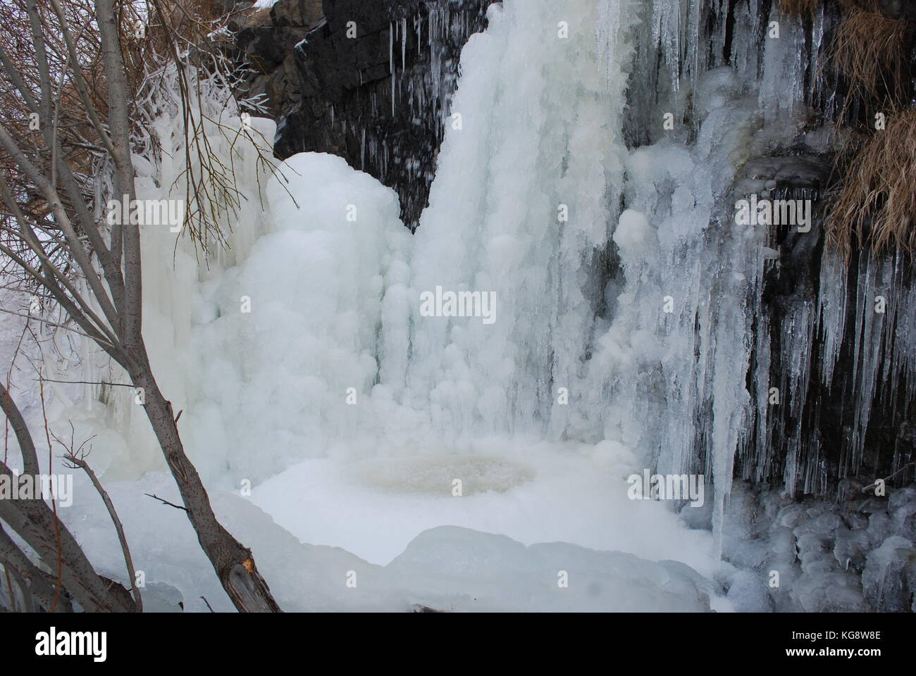 Water from a waterfall freezing onto the rocks, and on the ground ...