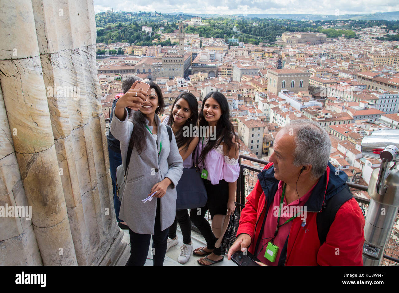 A group of three female tourists pose for a selfie on the outer balcony ...