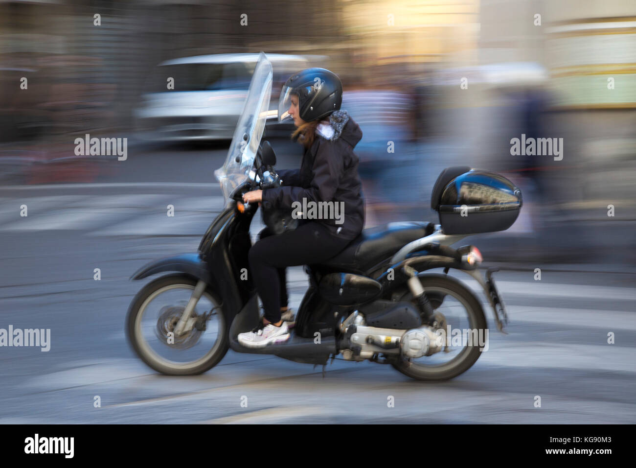 A woman moped rider travelling in the streets of Florence on a black ...