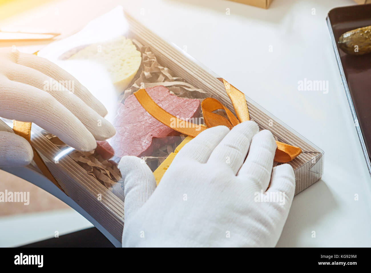 close-up packer with sterile white gloves packs a set of chocolates ...
