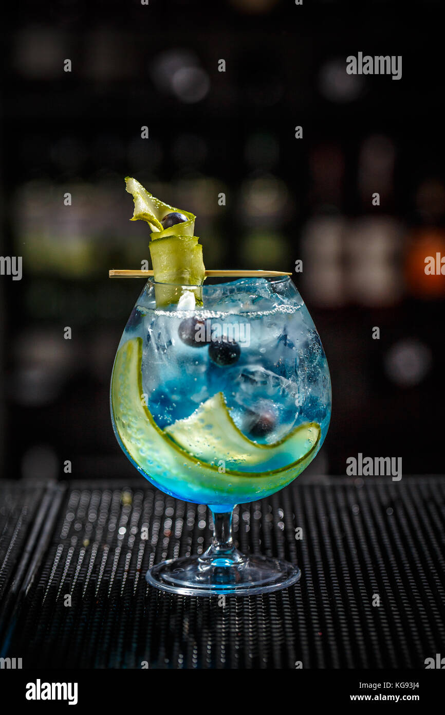 Blue gin tonic with cucumber served on the bar counter Stock Photo - Alamy