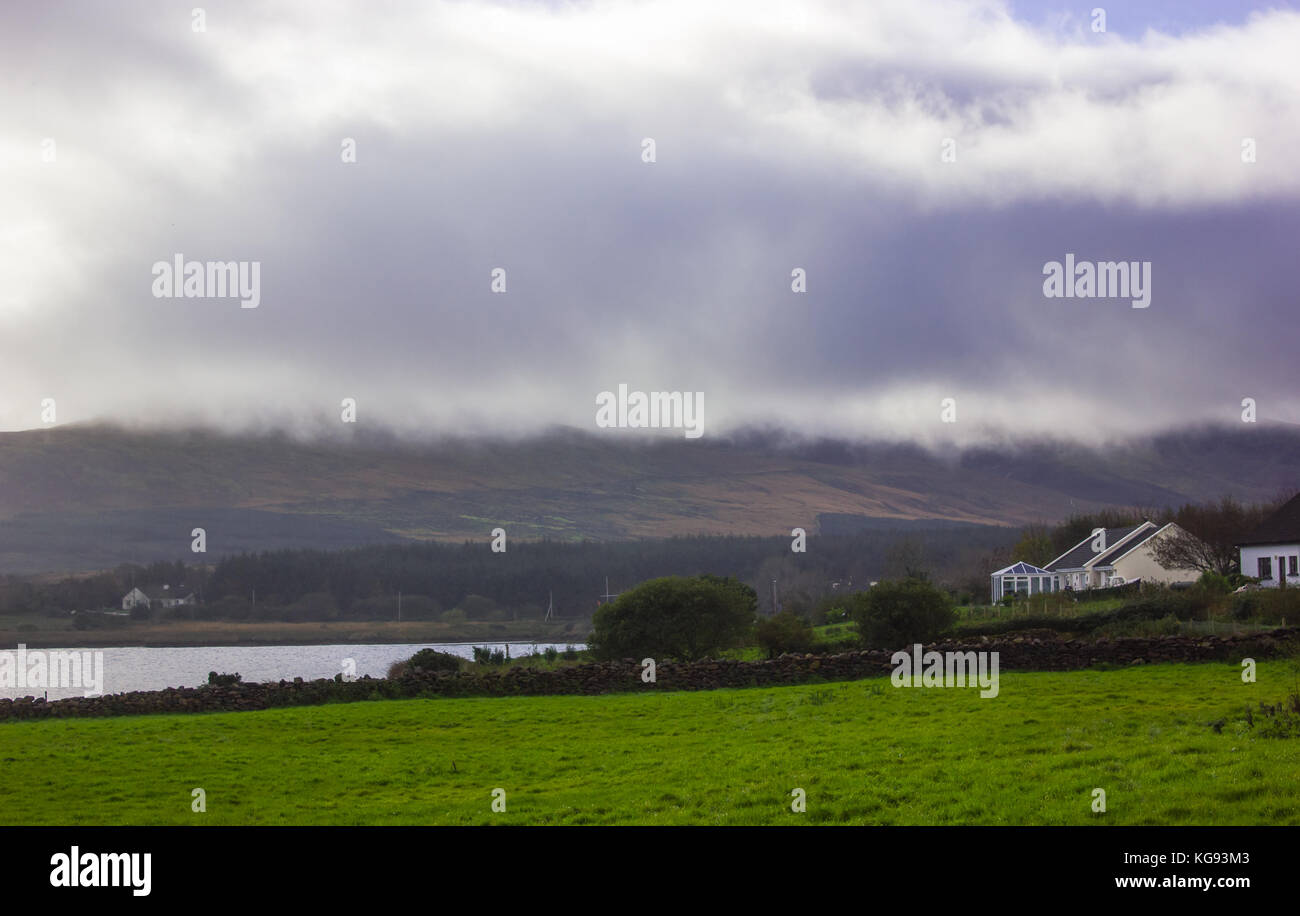 view of the sea shore in Ireland rain clouds hanging over the mountains ...
