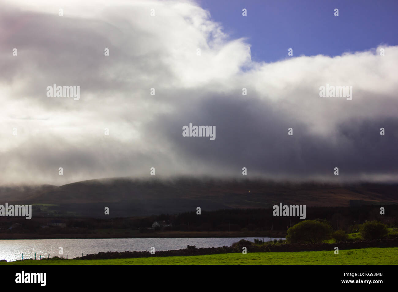 view of the sea shore in Ireland rain clouds hanging over the mountains ...