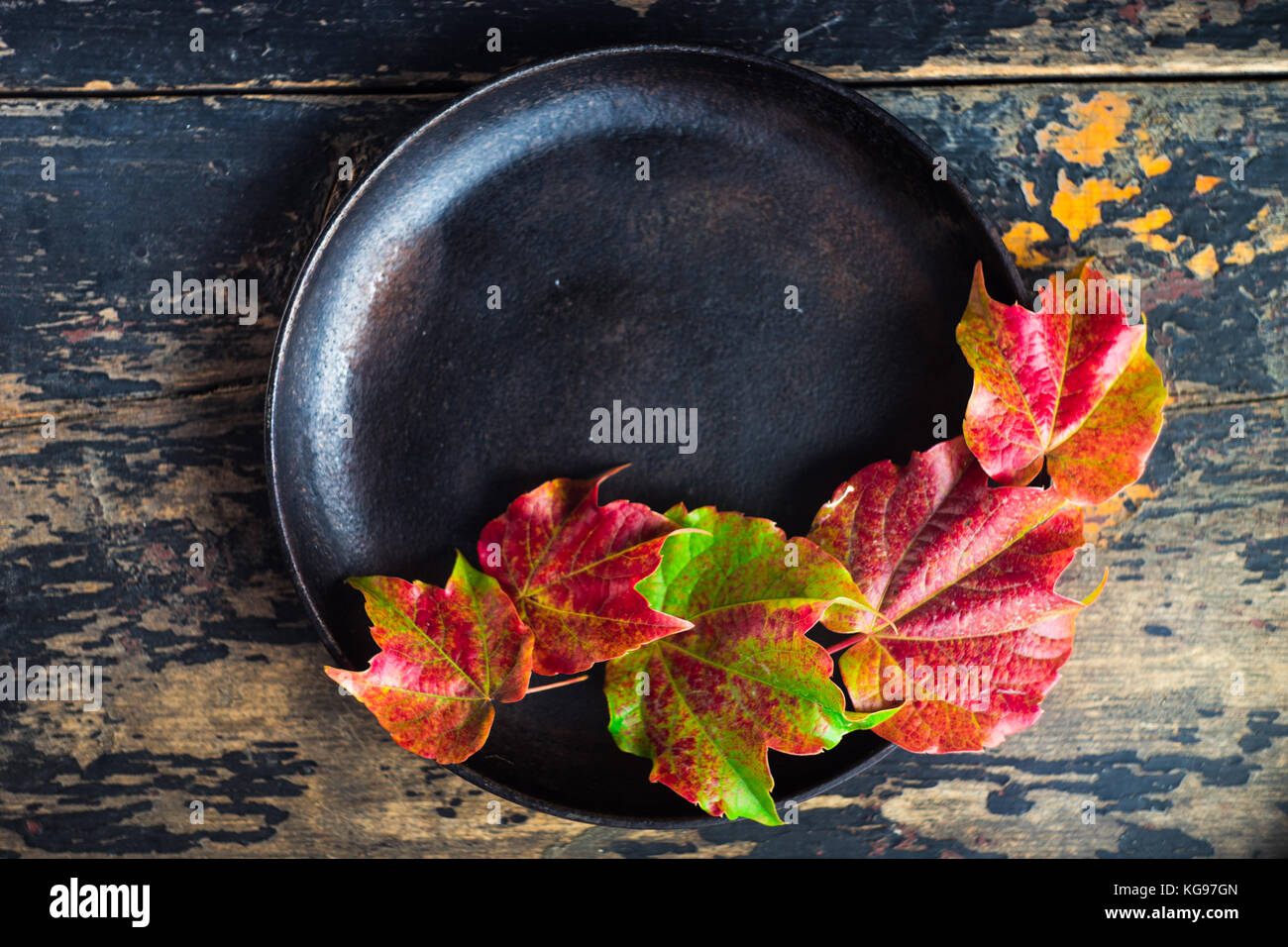 Festive autumnal table setting with bright red and yellow leaves with ...
