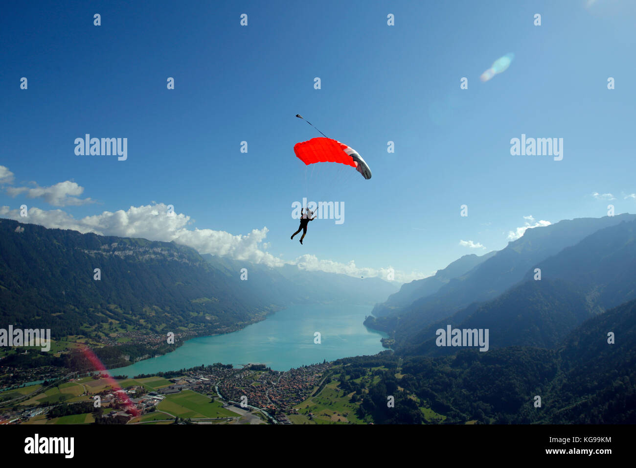 Skydiver is flying under canopy high in the sky over a beautiful lake ...