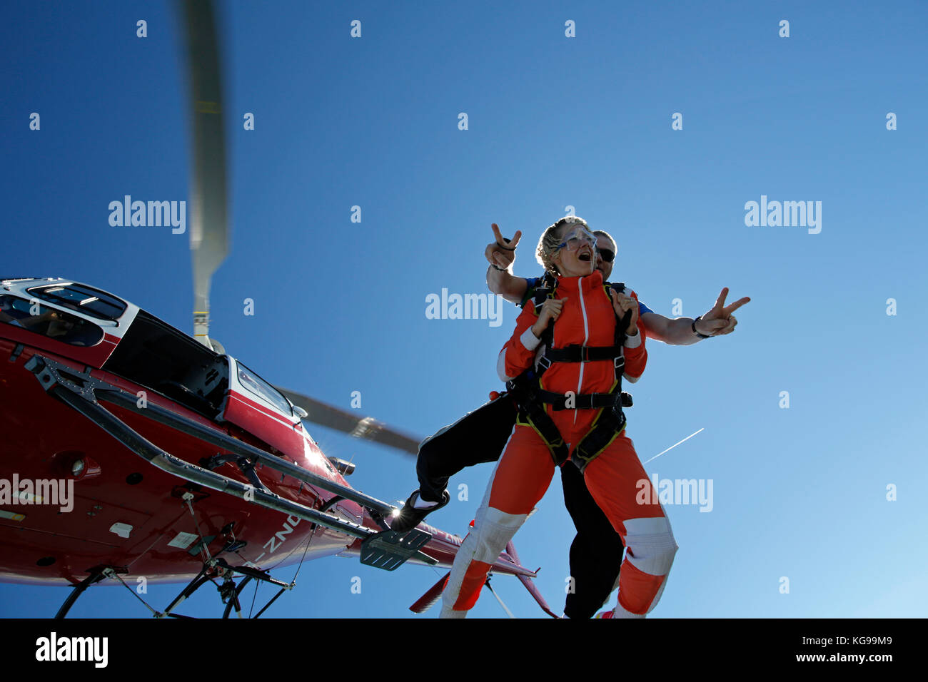 This tandem skydiving couple is jumping out of a helicopter over a ...