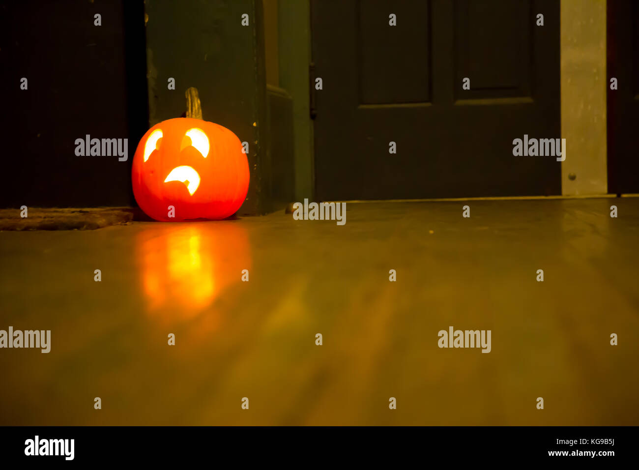 Illuminated orange halloween pumpkin floor door night Stock Photo - Alamy
