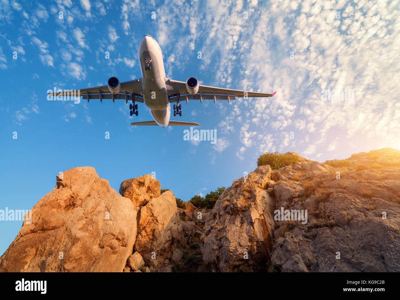 Big white aircraft is flying over rocks at sunset. Landscape with ...