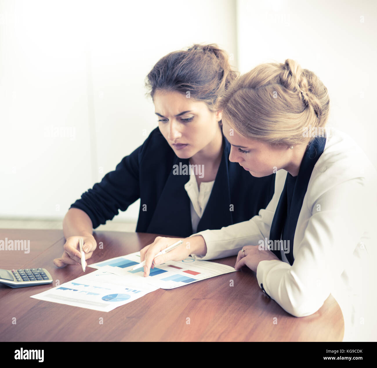 Business women pointing at diagrams discussing financial reports at ...