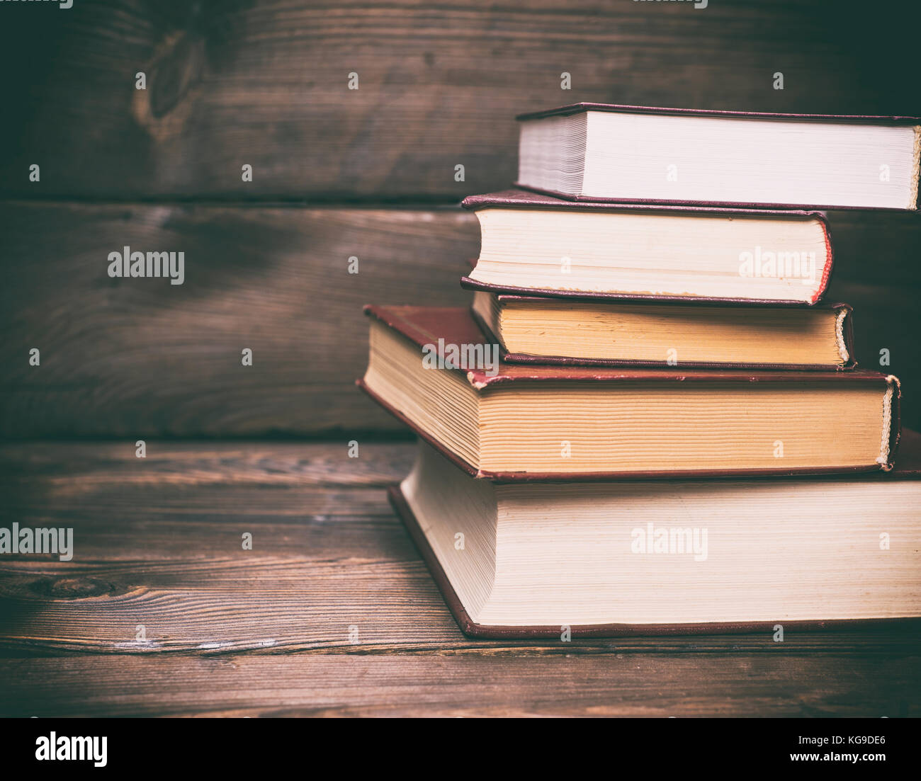 stack of closed books on a brown wooden background, empty space on the ...