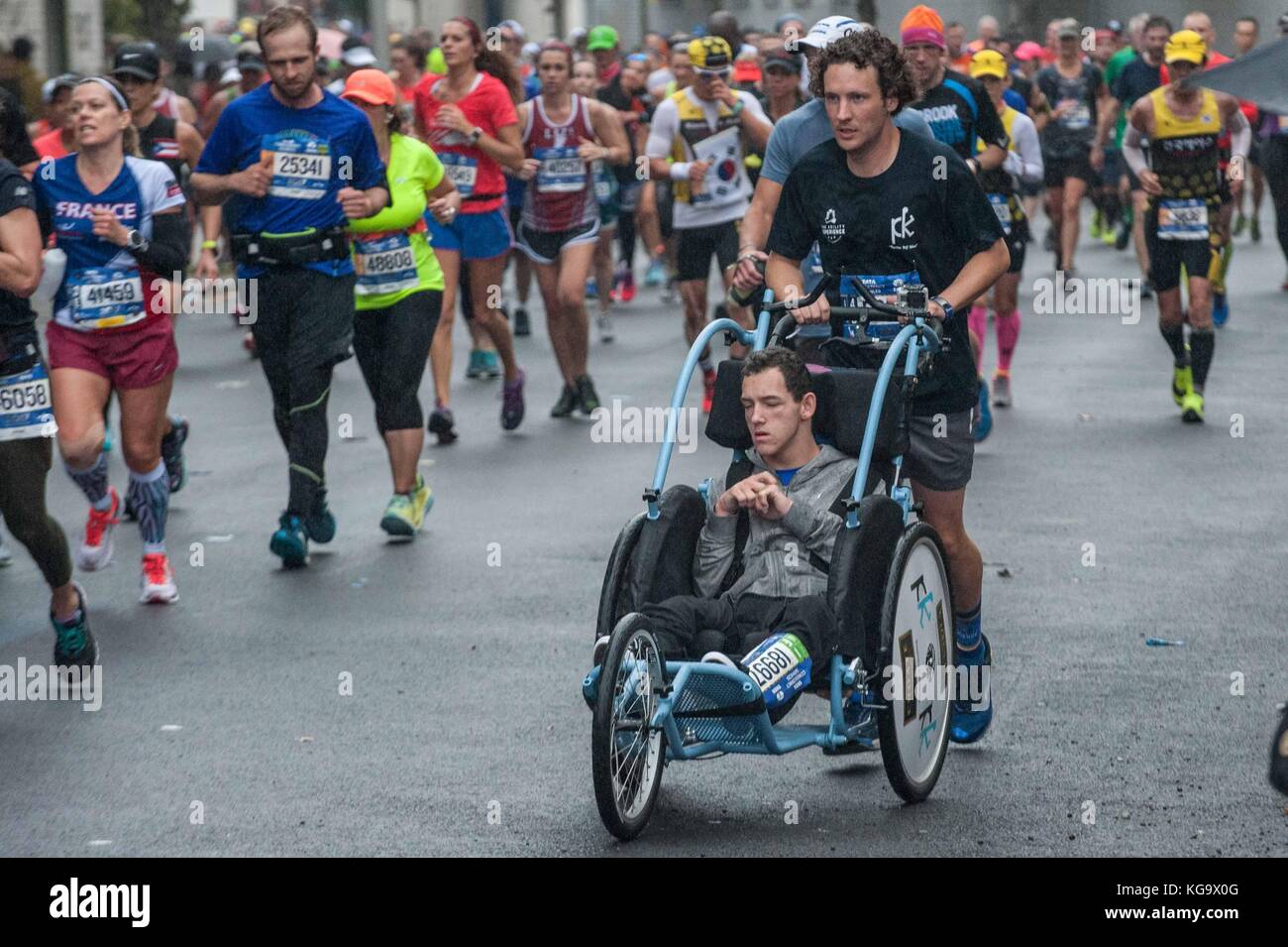 New York, USA. 5th Nov, 2017. An able bodied runner pushes a disabled ...