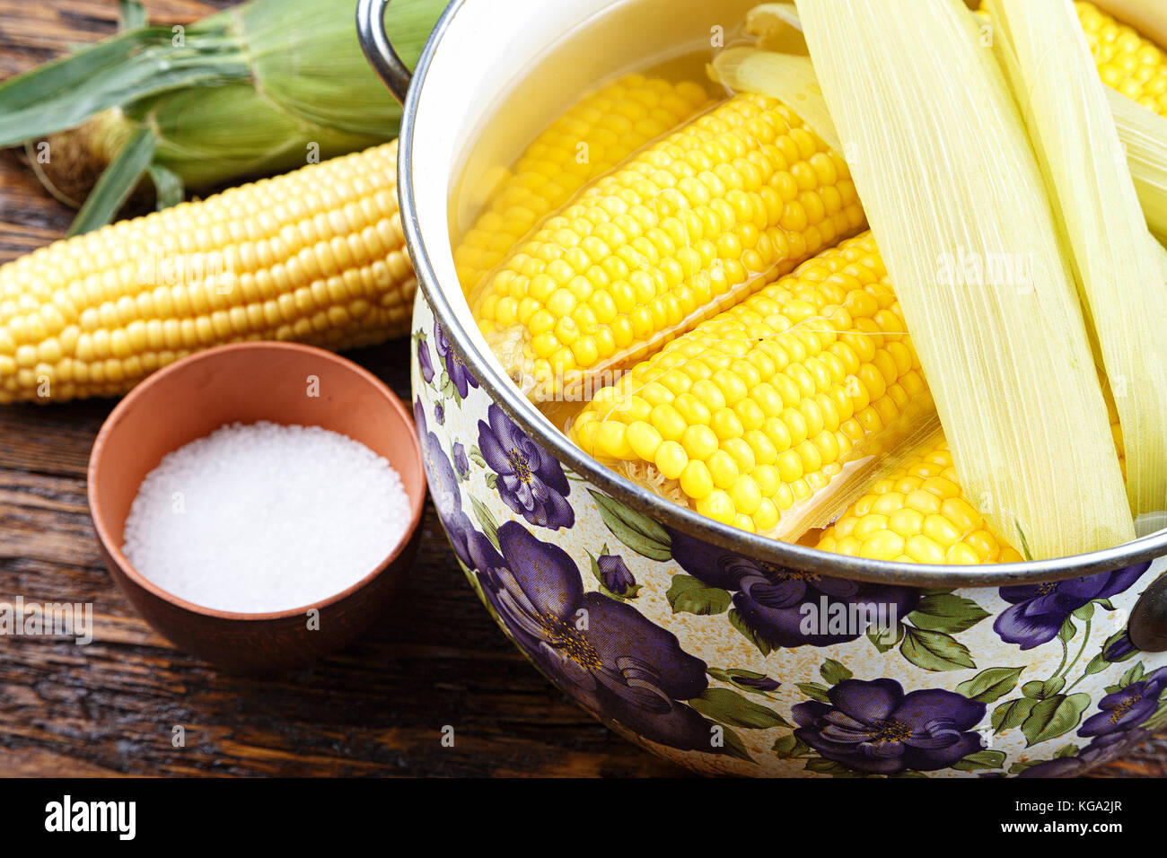 Cooked and raw corncobs on a dark wooden background Stock Photo - Alamy