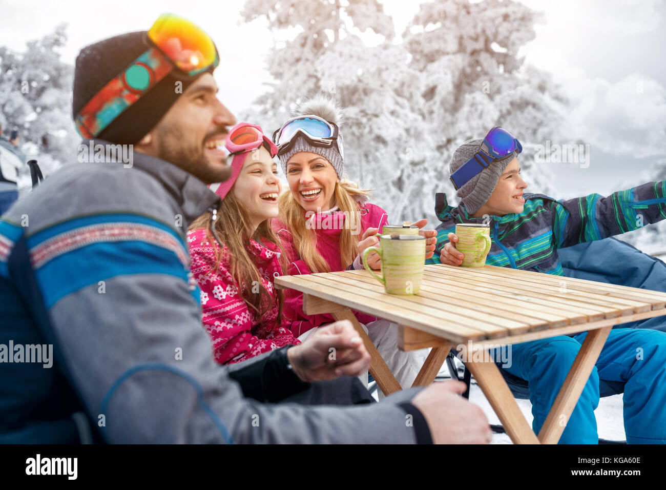 Family laughing and takes tea break during skiing on the mountain ...