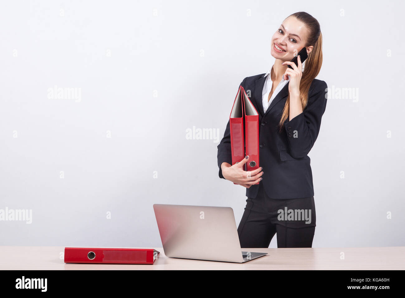 young girl manager is on a white background next to a table with Stock ...