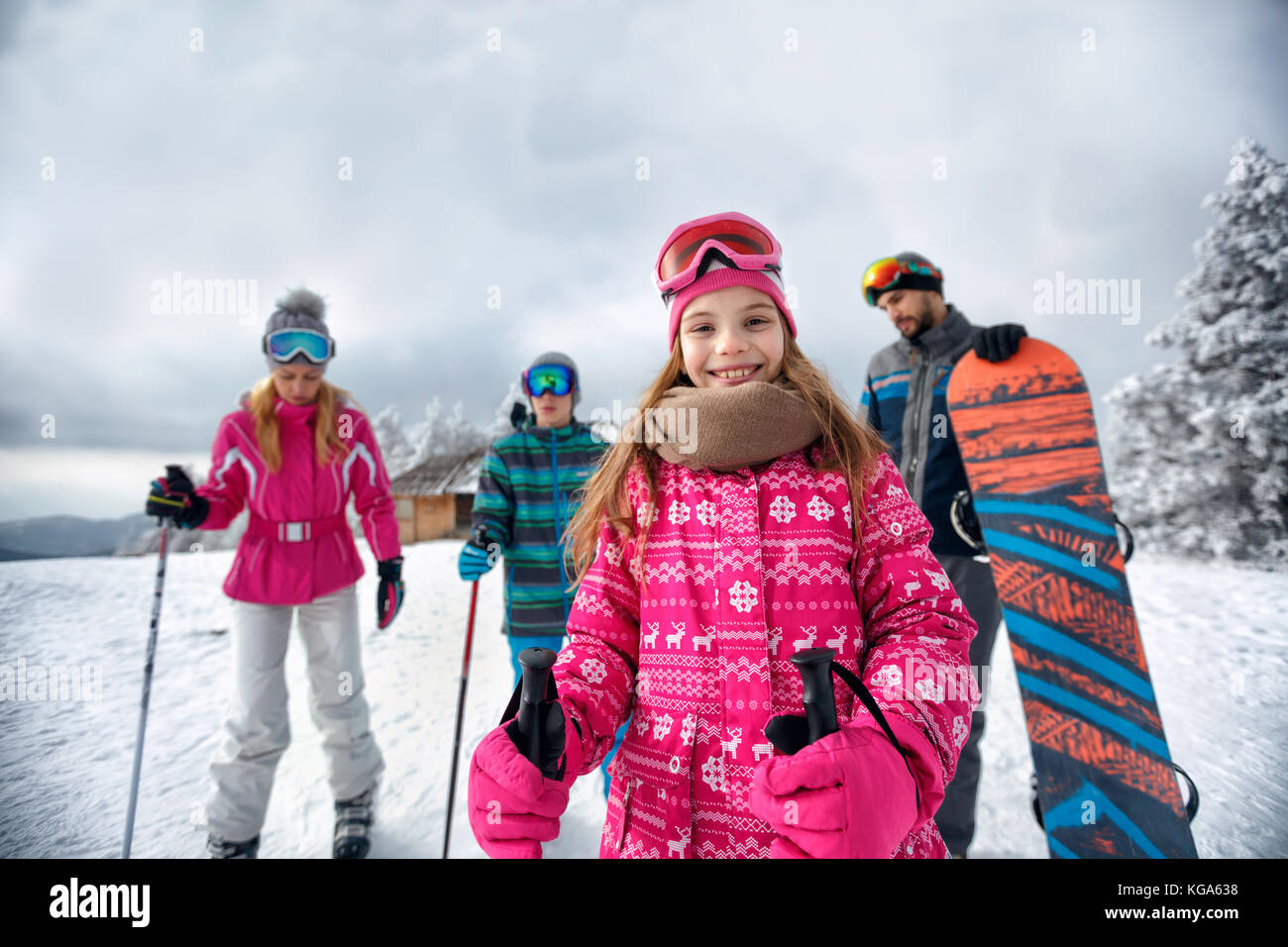 young smiling girl with family on ski slope on vacation in mountain ...