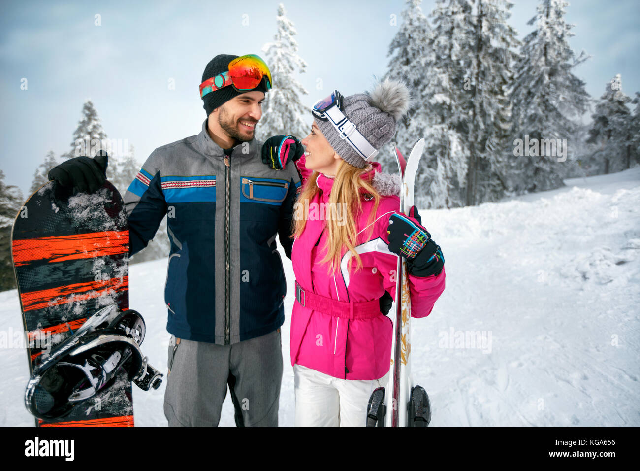 young couple skiing and snowboarding enjoying in snowy mountains ...