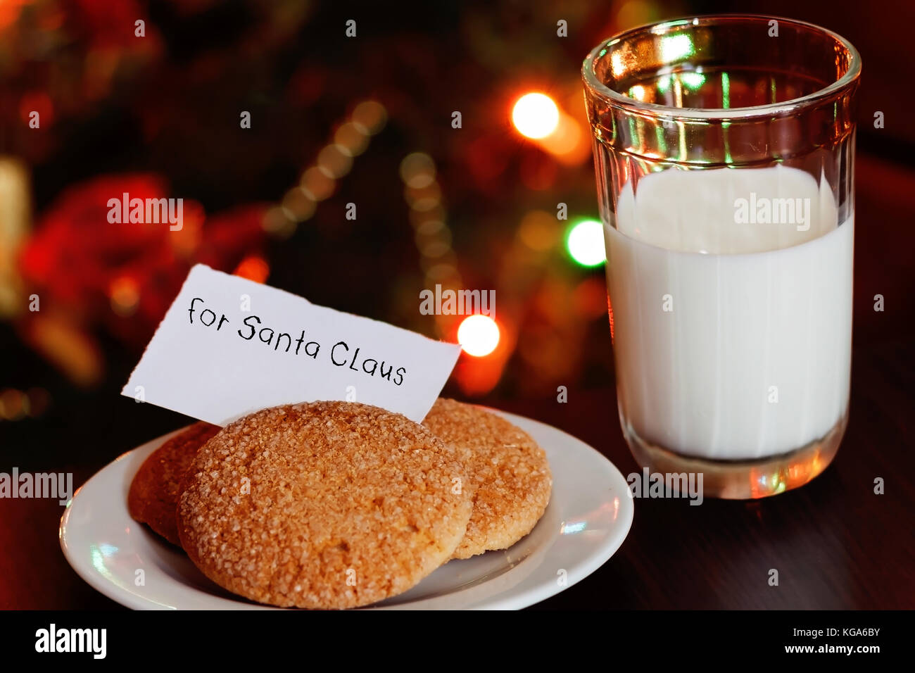 Christmas cookies and milk with note for Santa in front of lights of ...