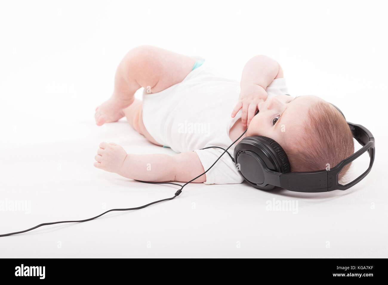 charming baby on a white background with headphones listening to Stock ...