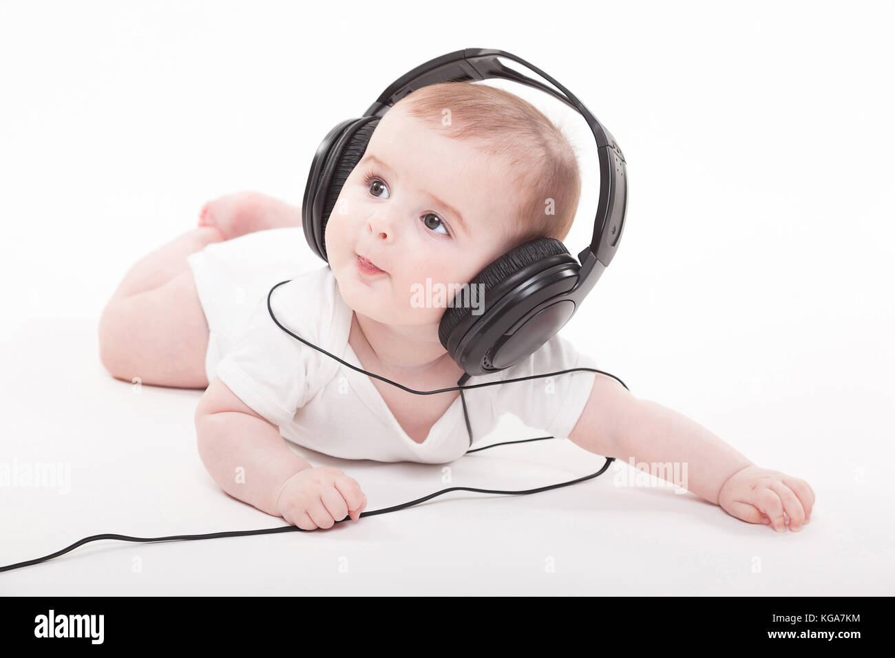 charming baby on a white background with headphones listening to Stock ...