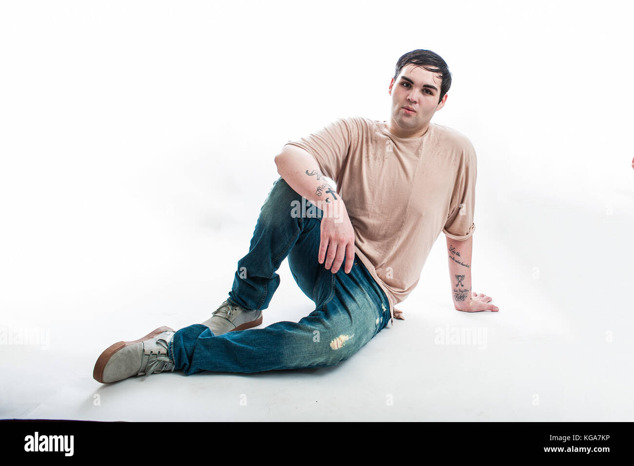 Fair skinned young man seated on floor with arm draped over knee Stock ...