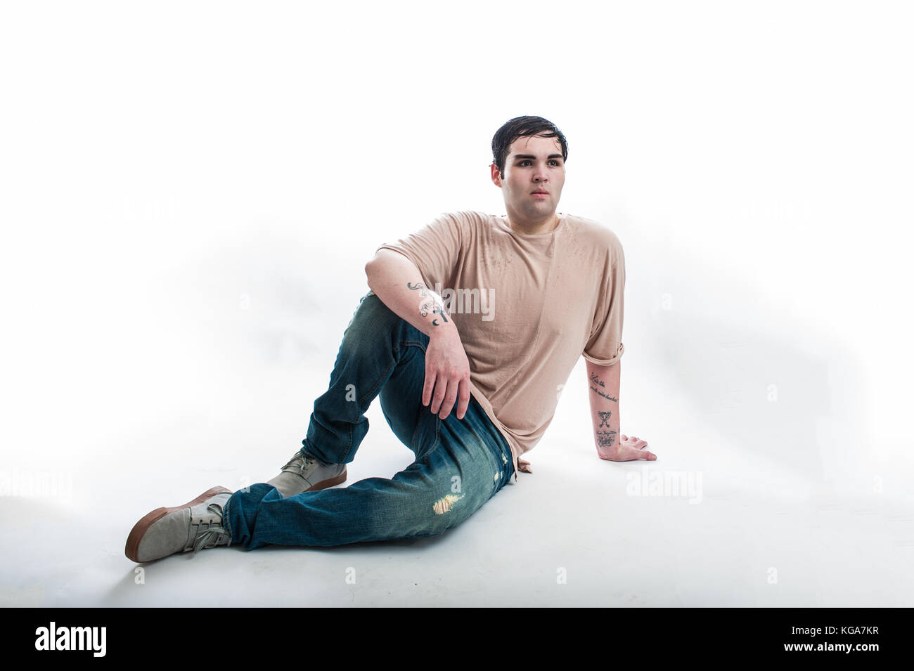 Fair skinned young man reclined on the white background floor resting ...
