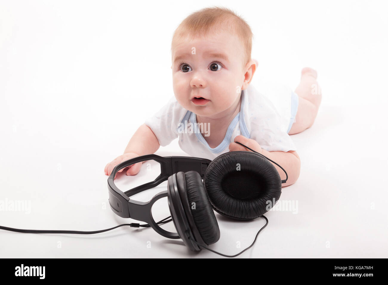 charming baby on a white background with headphones listening to Stock ...