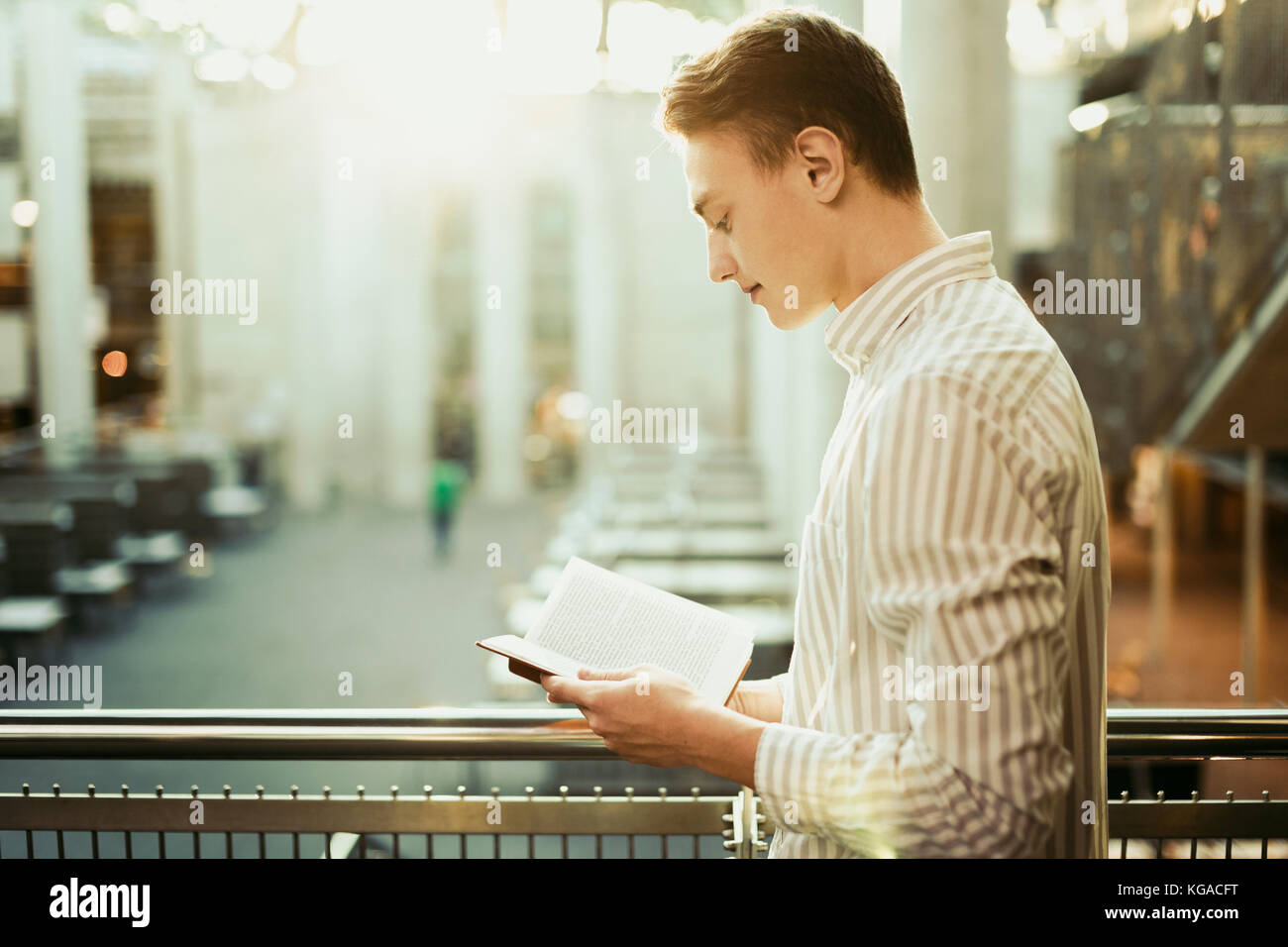 Man stsnd on the library and read book with blur background sun light ...