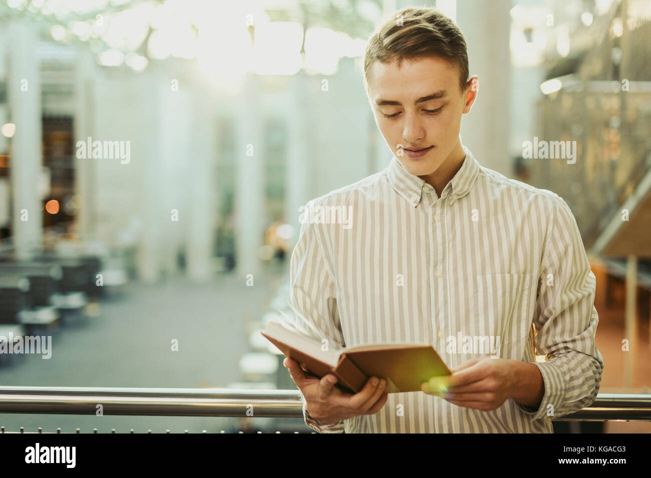Man stsnd on the library and read book with blur background sun light ...