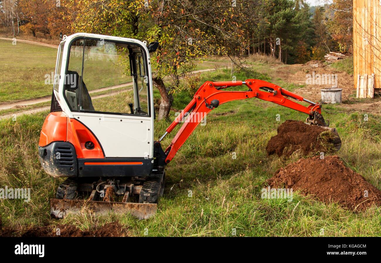 Mini excavator on a building site. Excavation work. The excavator works ...