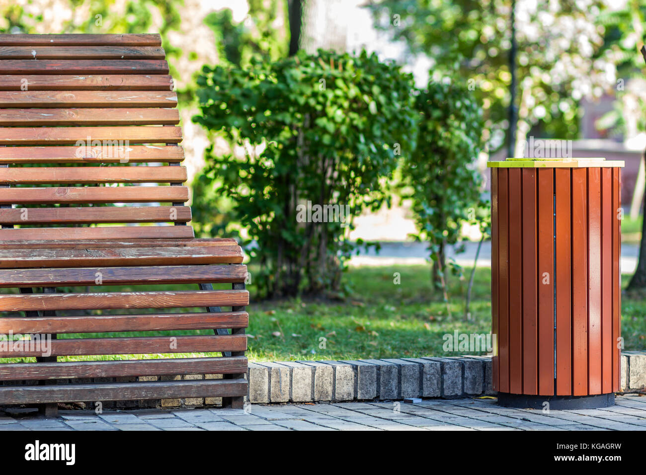Wooden bench and a garbage bucket in park Stock Photo - Alamy