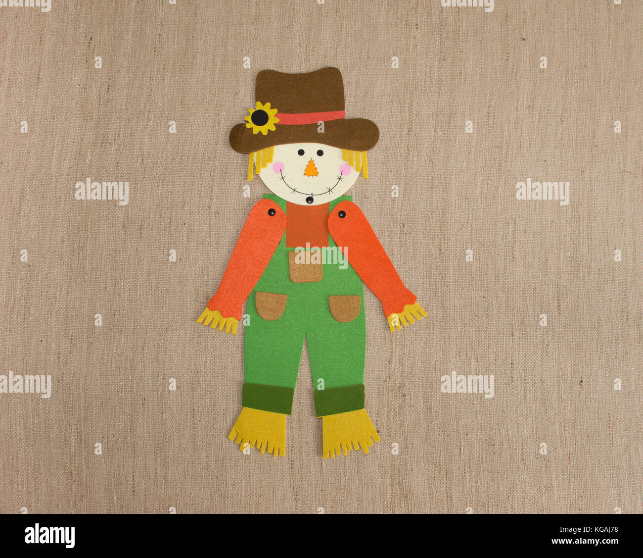 A felt scarecrow wearing orange, yellow, bright green and brown on a ...