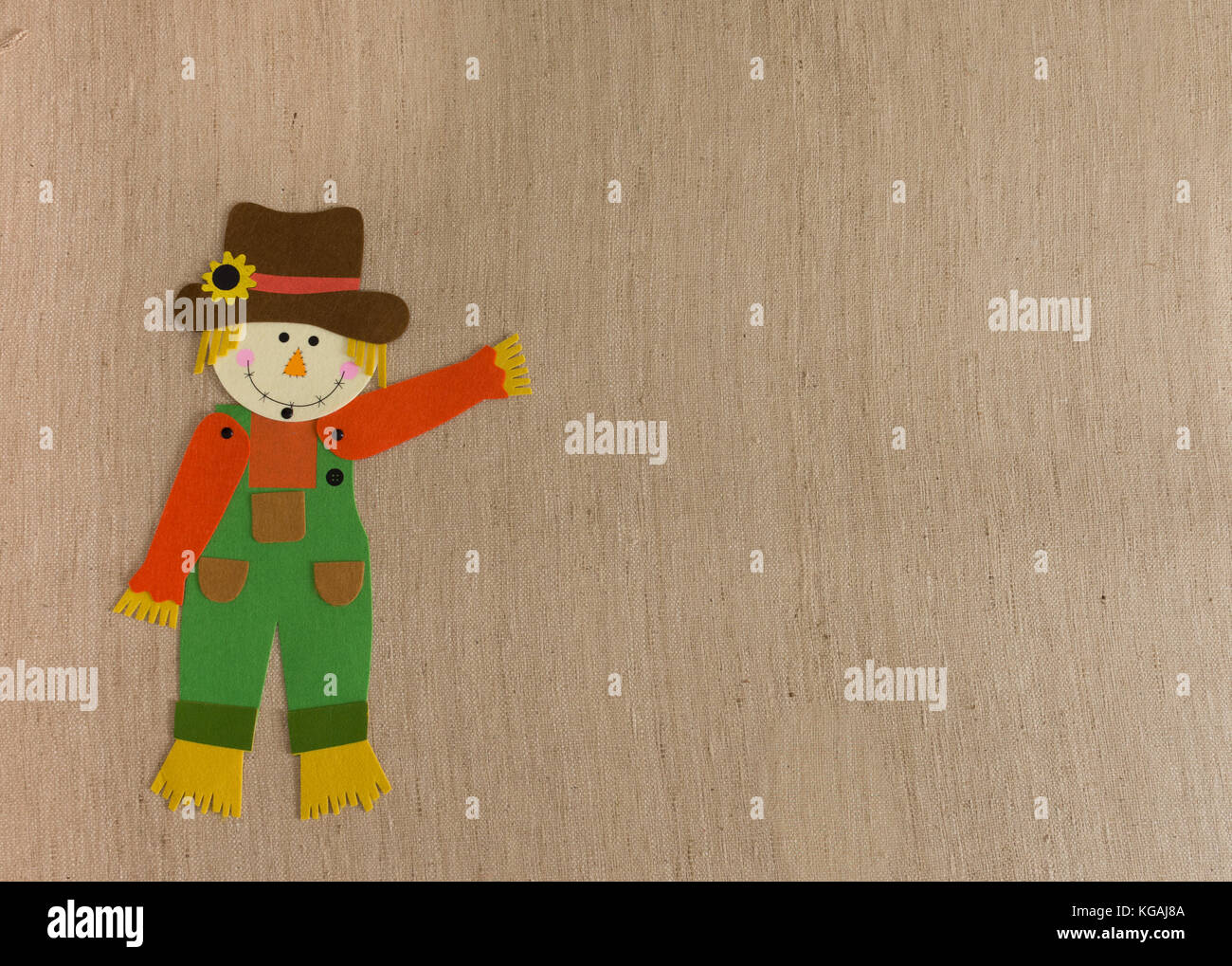 A waving felt scarecrow wearing orange, yellow, bright green and brown ...