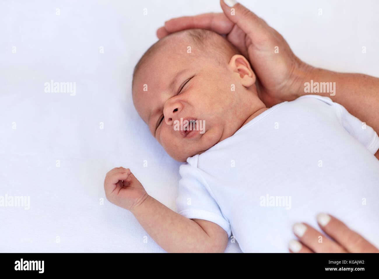 Woman's hands cradling a newborn babys head as baby is preparing to cry ...