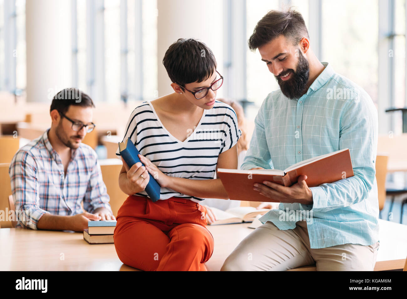 Young attractive students spending time in library Stock Photo - Alamy