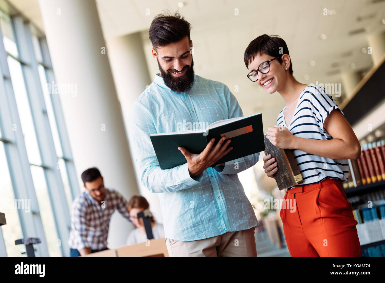 Young attractive students spending time in library Stock Photo - Alamy