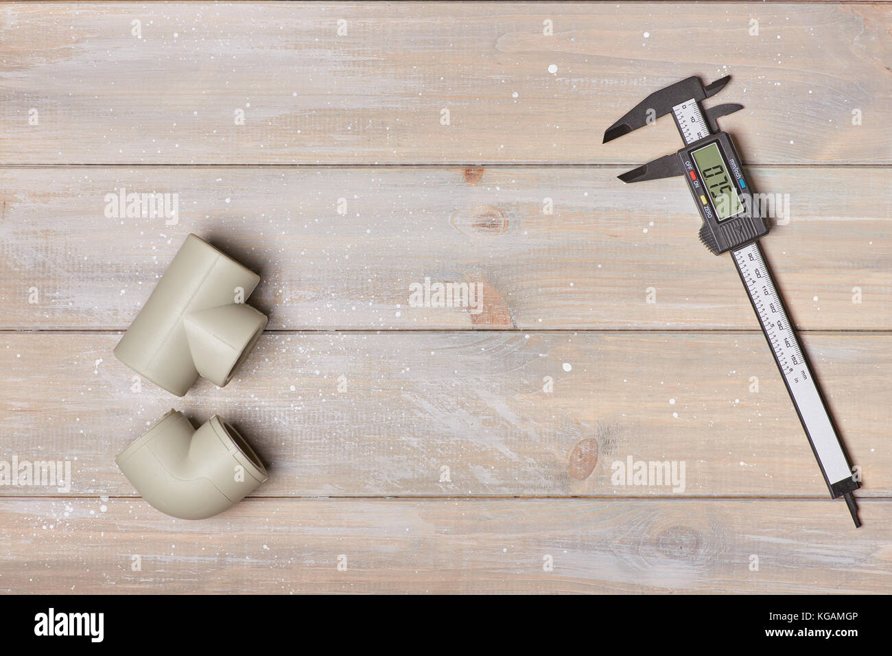 Electronic calipers and two plastic pipes lie on a wooden table. In the ...
