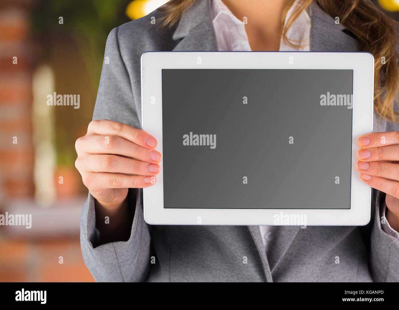 Digital composite of Hand holding tablet with warm interior background ...