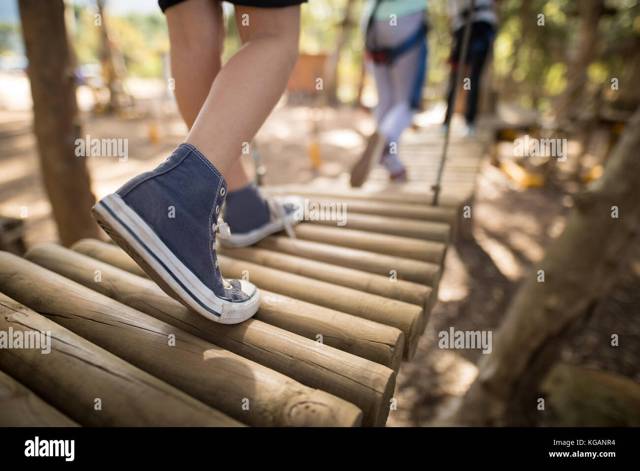 Low section of kid crossing wooden bridge on a sunny day Stock Photo ...