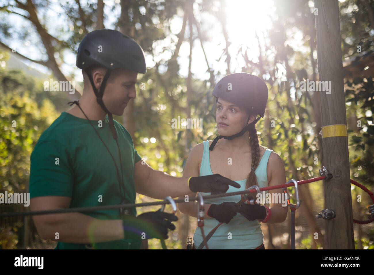 Coach assisting trainee in zip line on a sunny day Stock Photo - Alamy
