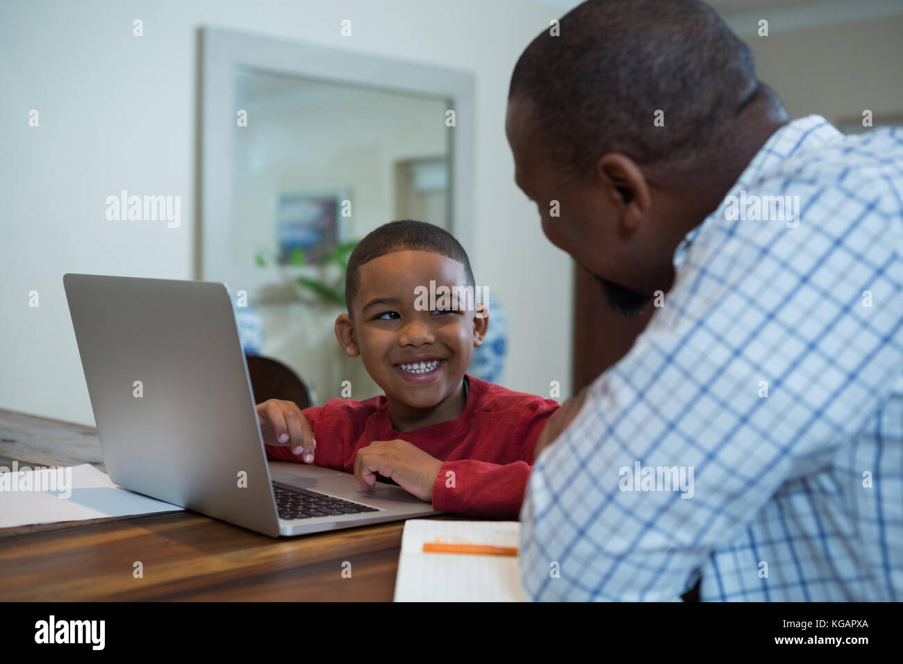 Father and son using laptop in living room at home Stock Photo - Alamy