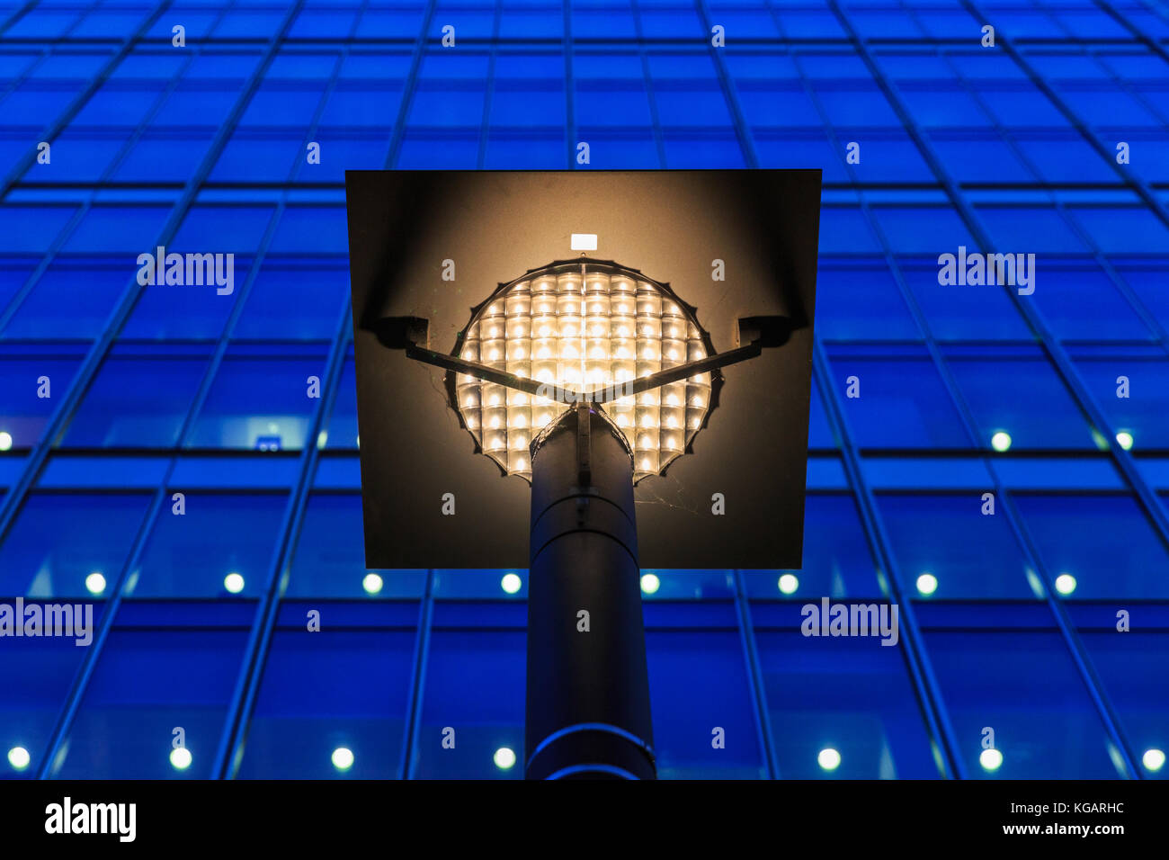 View up modern street light with cold blue lit office building in ...