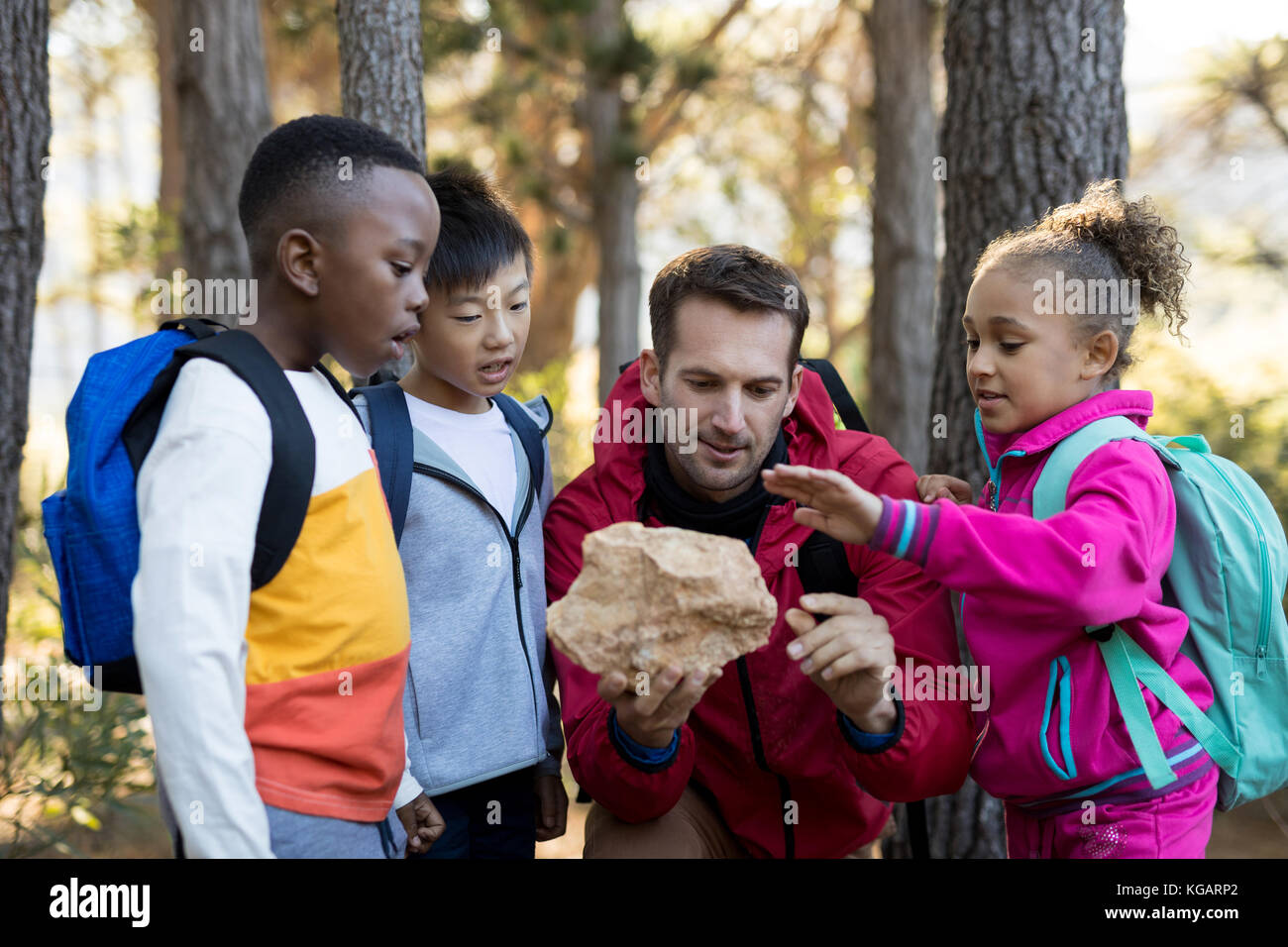 Teacher and kids examining rock in park Stock Photo - Alamy