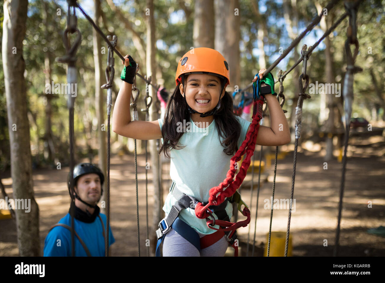 Portrait of cute girl crossing zip line on a sunny day Stock Photo - Alamy