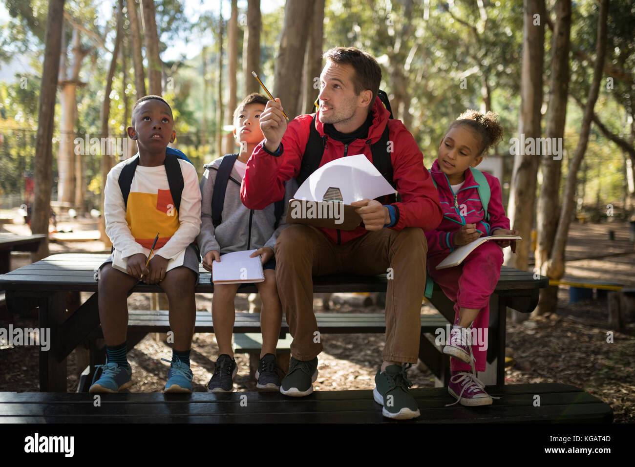Teacher assisting kids in studying at park Stock Photo - Alamy